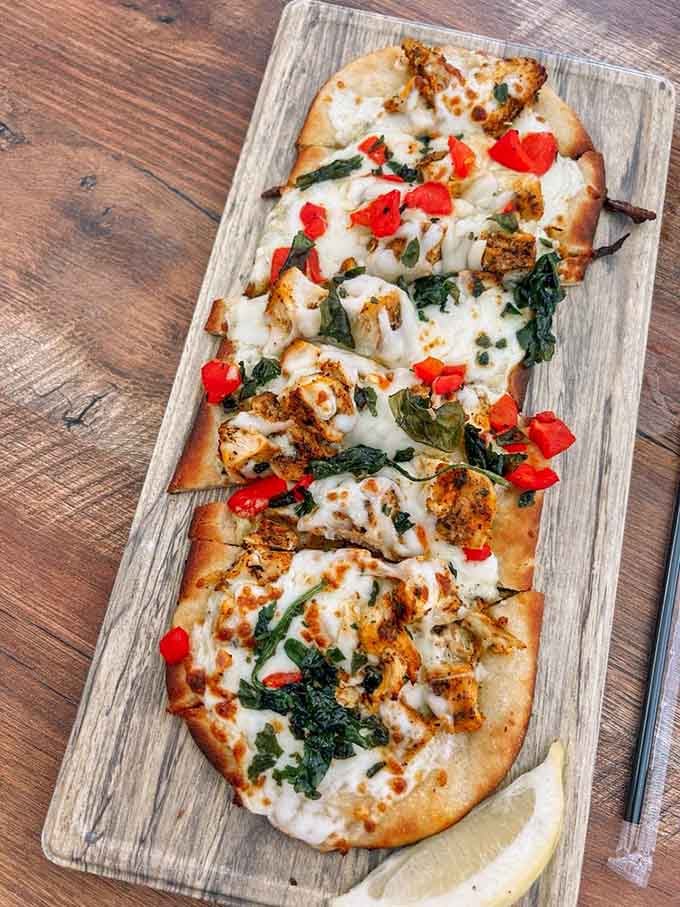 Chicken pesto flatbread arrives golden and bubbling, ready to complement whatever wine you're currently enjoying.