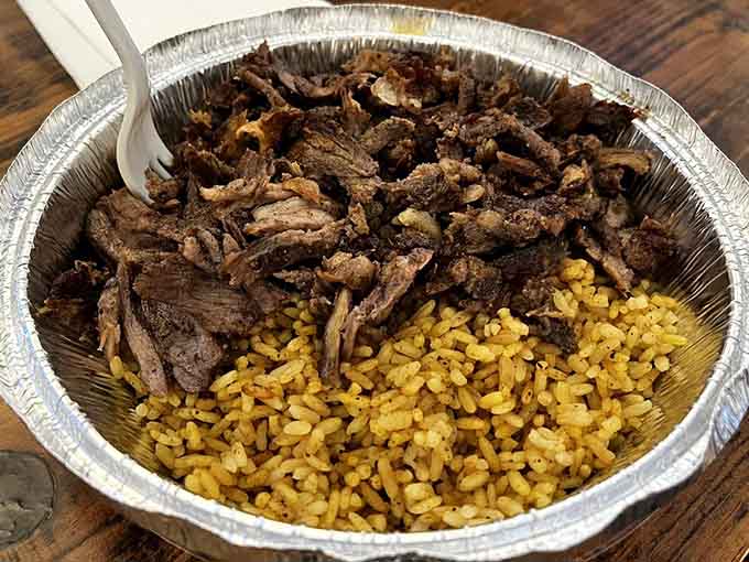 Succulent lamb over golden rice in a to-go container, proving takeout can be just as spectacular as dining in.