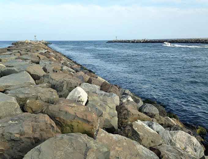 These weathered jetty rocks have witnessed countless tides, standing sentinel like nature's own permanent beach installation art.