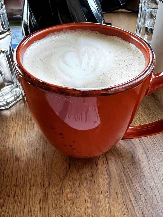 A perfectly crafted latte in a cheerful mug, because even your coffee deserves to feel special here.