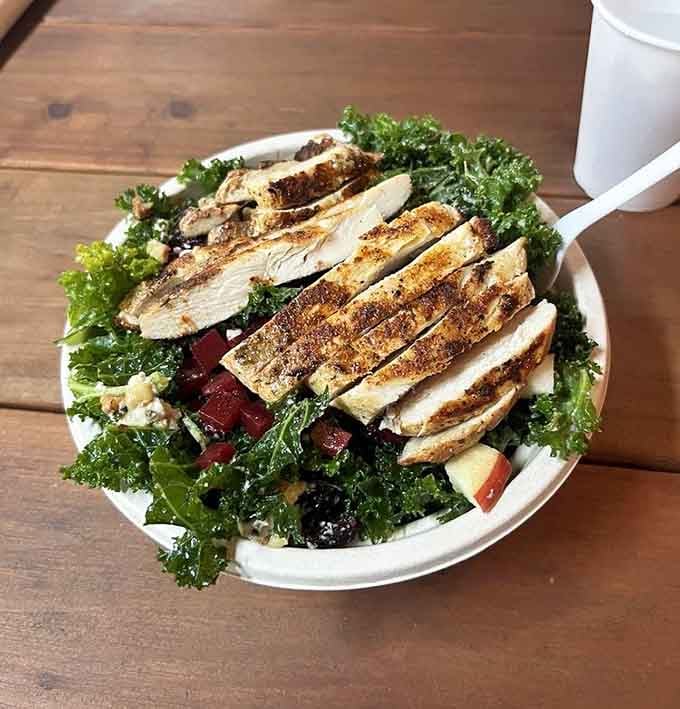 A kale salad topped with perfectly seasoned chicken that makes eating your greens feel less like a chore, more like a choice.