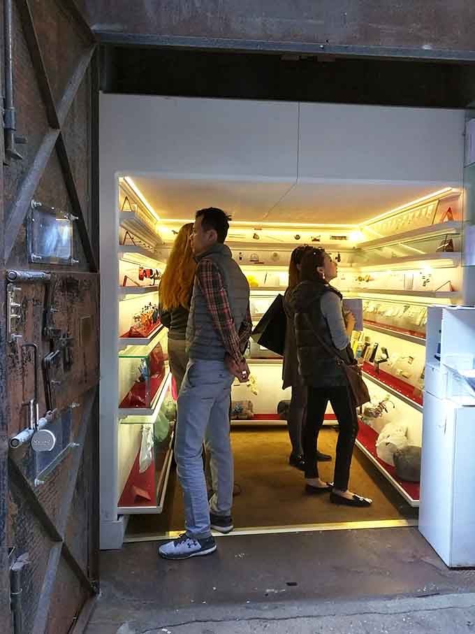 Two visitors contemplate the illuminated shelves like they're decoding the Rosetta Stone, which isn't far from the truth.