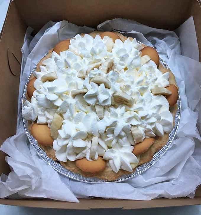 Banana cream pie piled high with whipped clouds, making every calorie absolutely worth the indulgence ahead.