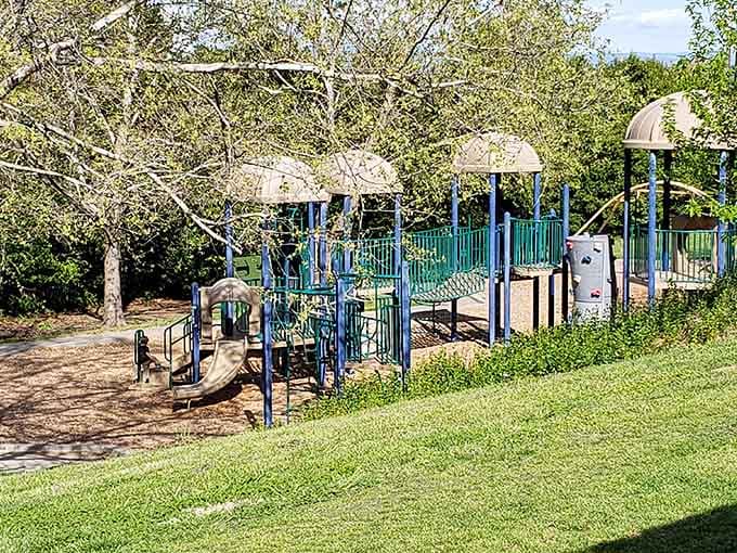 More playground equipment surrounded by grass and trees, not concrete and the sound of traffic helicopters overhead.