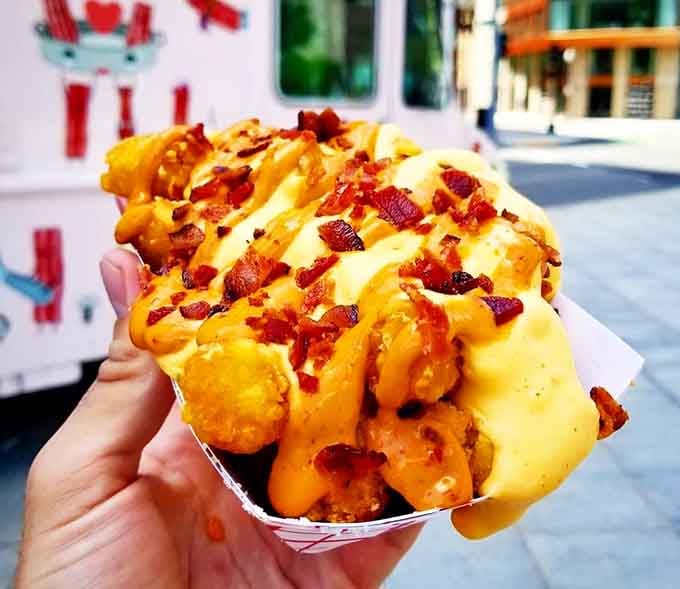 Loaded tots buried under cheese and bacon bits, proving that potatoes are just vehicles for delivering maximum indulgence.
