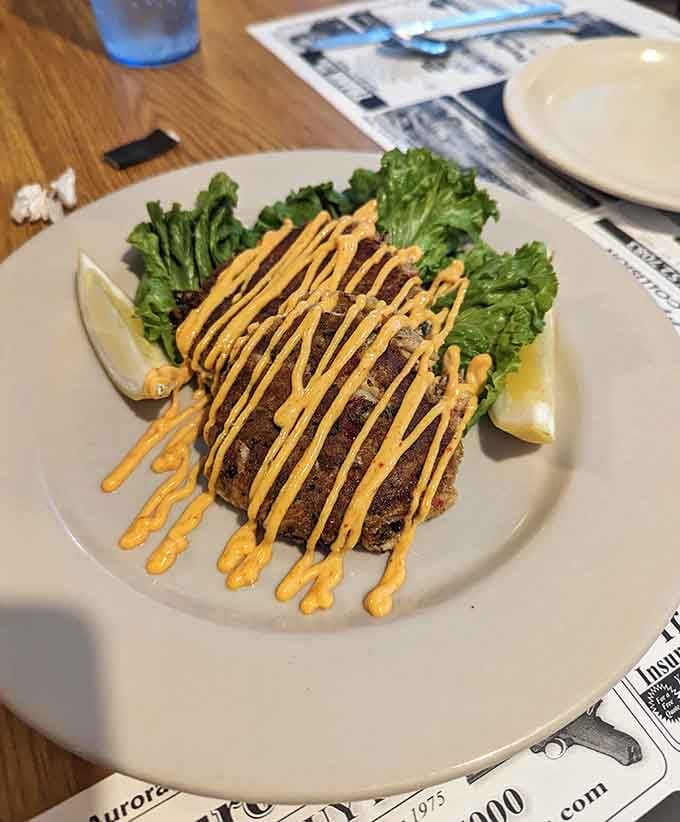 Crab cakes drizzled with sauce on fresh greens show the menu goes beyond typical diner fare beautifully.