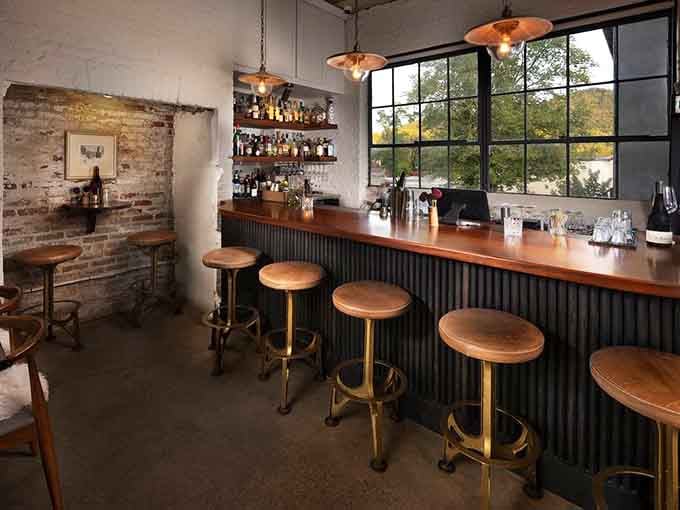 The bar area blends rustic charm with modern style, perfect for sipping something special before your meal.