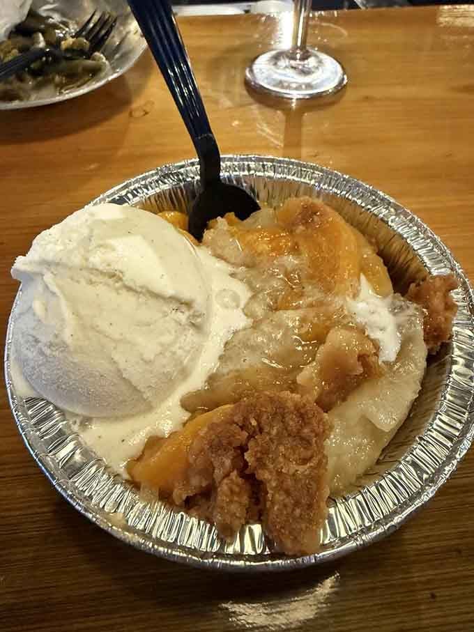 Peach cobbler with vanilla ice cream melting into warm fruit, because Georgia knows how to end meals right.