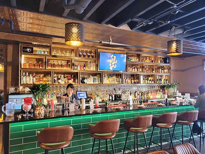 The sophisticated bar area with its emerald tiles and extensive bottle collection sets a refined yet relaxed tone.