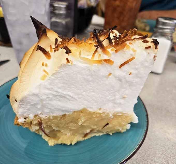 Coconut cream pie stacked so high it defies gravity and common sense in the most delicious way.