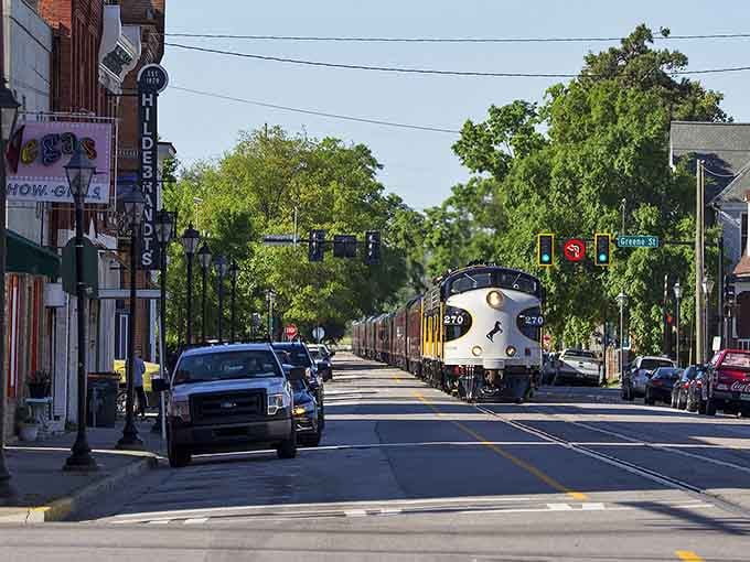 That vintage passenger train rolling down Main Street looks like it escaped from a 1950s postcard, headlight gleaming.