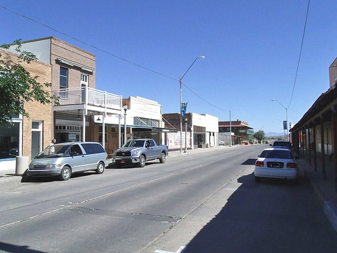 Simple storefronts stretch toward distant mountains under bright Arizona skies that seem to go on forever.