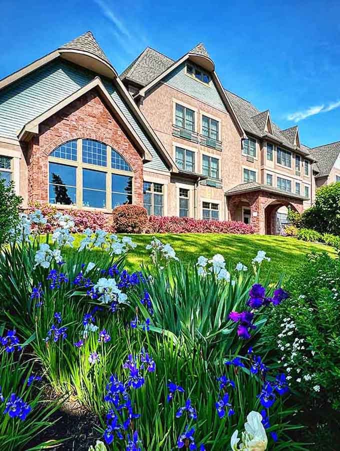 Spring blooms burst with purple and blue joy in front of this charming estate, proving nature knows how to accessorize.