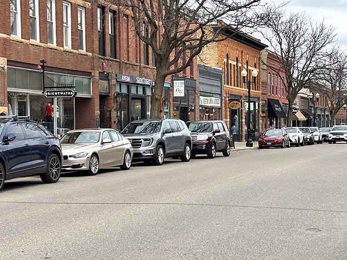 Parked cars line streets where horse-drawn carriages once clip-clopped past these same enduring brick storefronts daily.