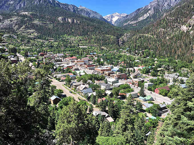 Snow-dusted peaks frame this alpine village where colorful rooftops pop against the evergreen forests like confetti at nature's party.