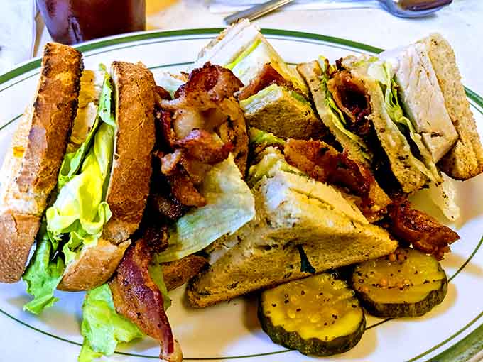 Club sandwich stacked so high it requires engineering skills to eat, accompanied by perfectly seasoned home fries naturally.