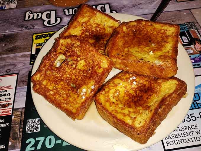 French toast so perfectly golden it practically glows, butter melting into every crispy-edged corner like liquid sunshine.