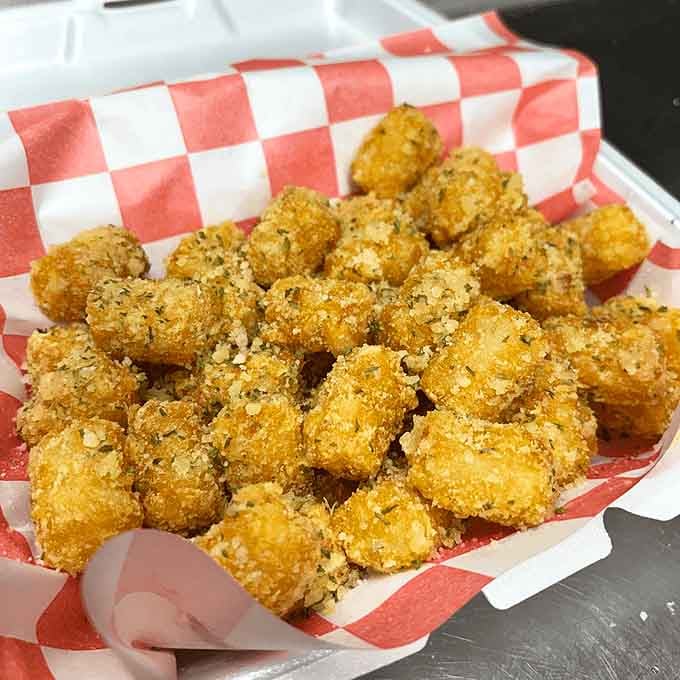 Those garlic parmesan-dusted tots gleam like little golden nuggets of crispy, savory heaven in a basket.