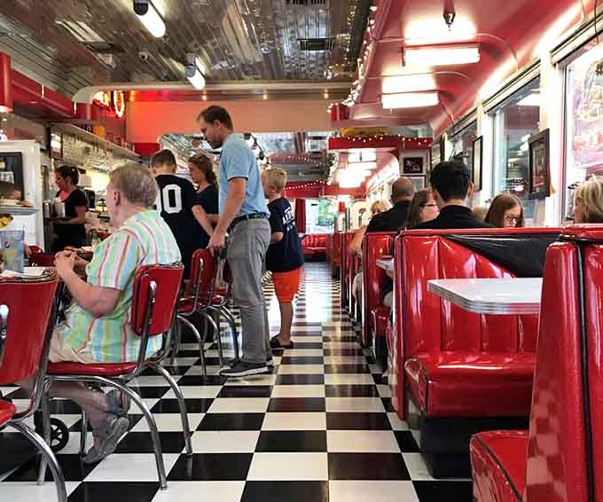 The checkered floor leads hungry folks past red booths toward counter seats where the real diner magic happens.