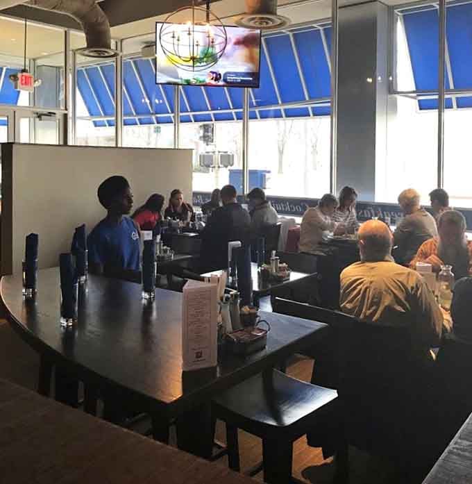 Happy diners gathered around tables bathed in natural light, sharing meals and conversation like the good old days.