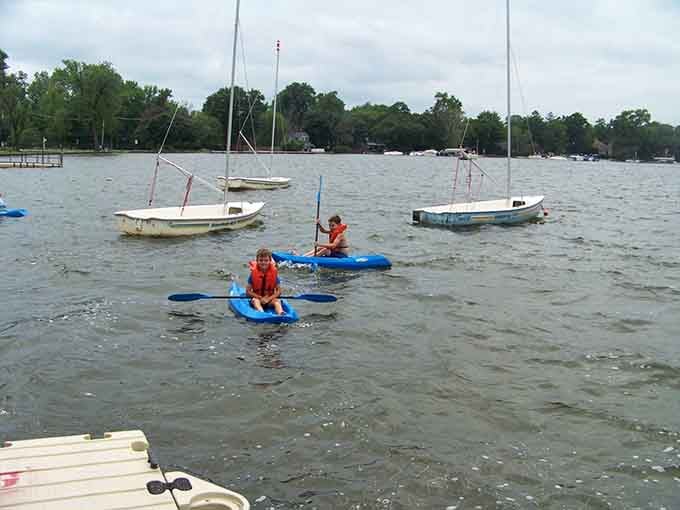 Kayaking youngsters navigate open water with life jackets and determination, learning independence one paddle stroke at a time.
