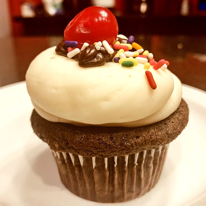 Sprinkles and a cherry on top transform this cupcake into a sundae experience without the spoon.