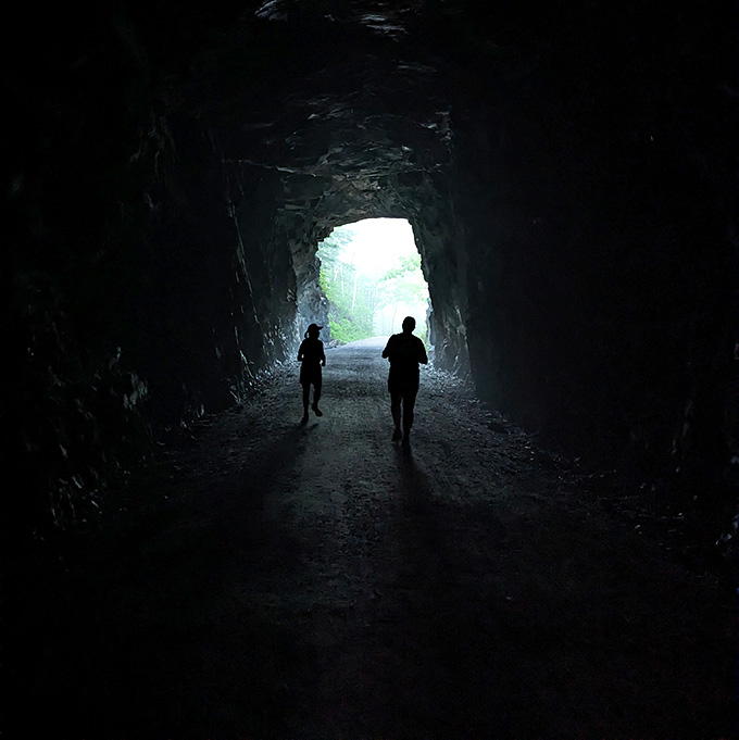 Stepping out from the shadows into the soft daylight, your path ahead reveals a rugged journey through this majestic stone passage.