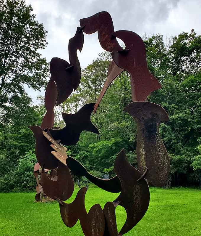 The textured beauty of this rustic sculpture provides a lovely contrast to the vibrant greens of the surrounding landscape today.