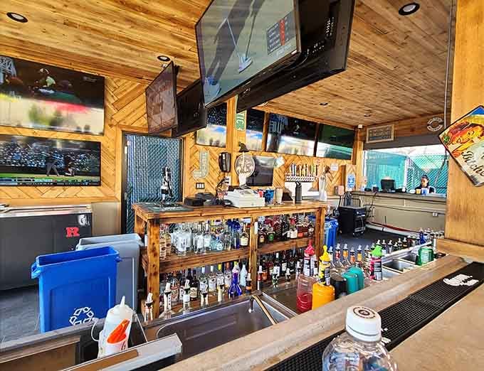The rustic wood bar setup with multiple TVs and a full liquor selection creates the perfect command center for watching games and making friends.