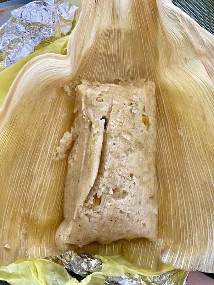 An elote tamale wrapped in corn husk&mdash;traditional preparation meets incredible flavor in every steamy bite.