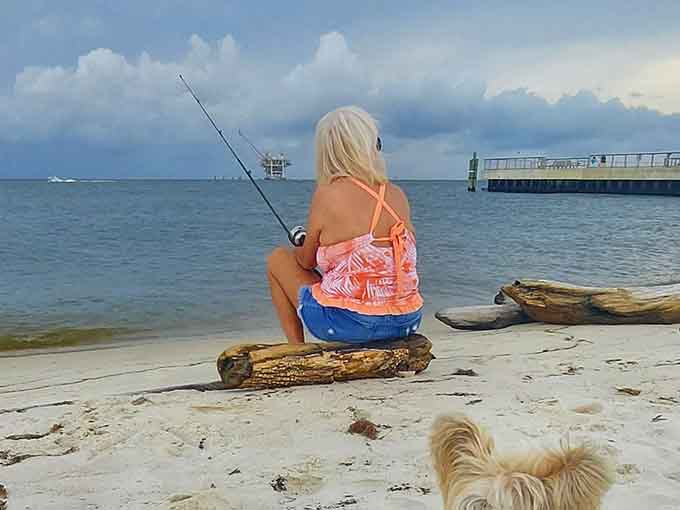 Fishing from driftwood with your furry companion nearby, living that Gulf Coast dream one cast at a time.