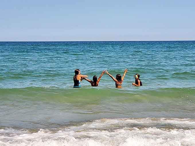 Friends raising hands in victory because they've discovered Lake Michigan's perfect swimming spot.