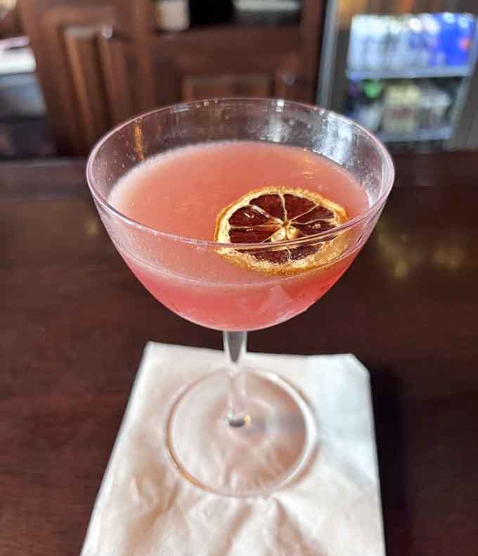 A raspberry martini garnished with dried citrus, proving that taverns can do cocktails as pretty as they are potent.