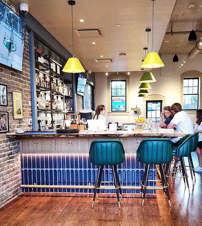 Colorful pendant lights and teal bar stools create a vibrant spot for drinks before your meal arrives.
