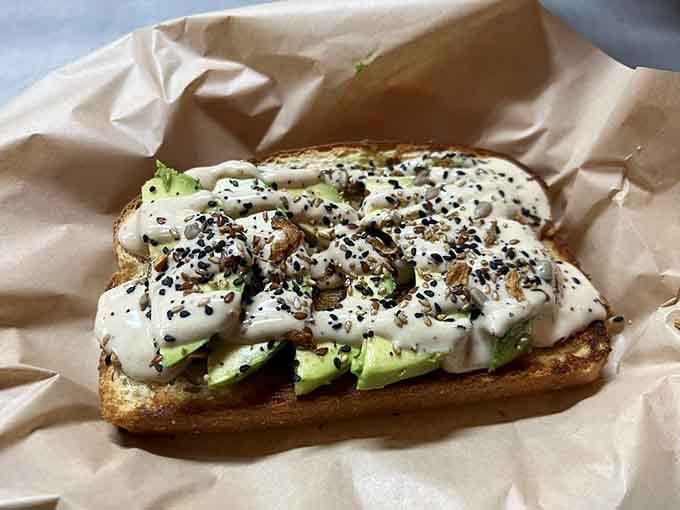 Avocado toast dressed up with sesame seeds and drizzle, proving that simple ingredients can create something genuinely Instagram-worthy.