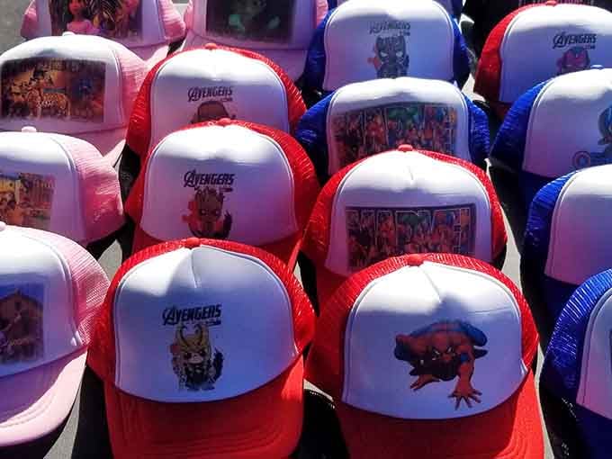 Avengers caps lined up like a superhero army, ready to protect heads from sun while declaring pop culture allegiance.
