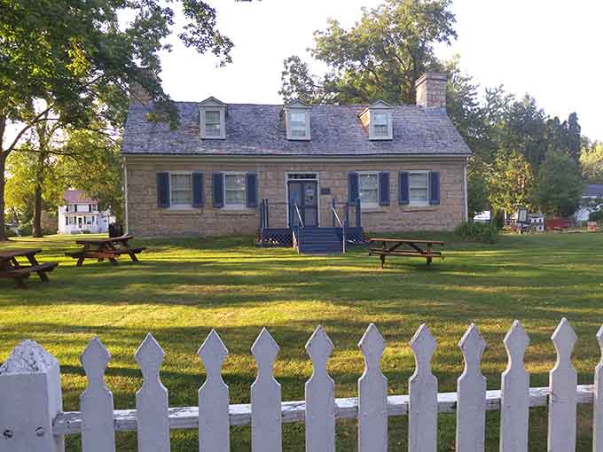 The Stone Cottage sits behind its white picket fence like a time capsule from when neighbors actually knew each other's names.