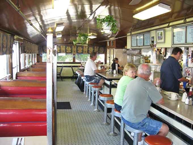 The view down the aisle shows classic diner architecture at its finest, all chrome and possibility.