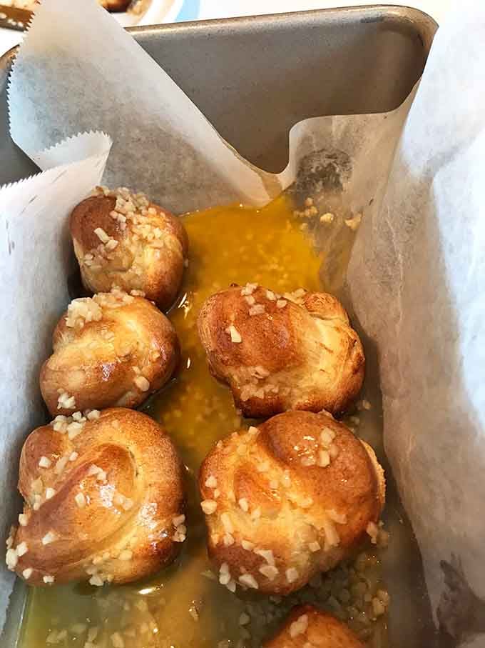 Garlic knots swimming in butter like they're training for the most delicious Olympics ever conceived.