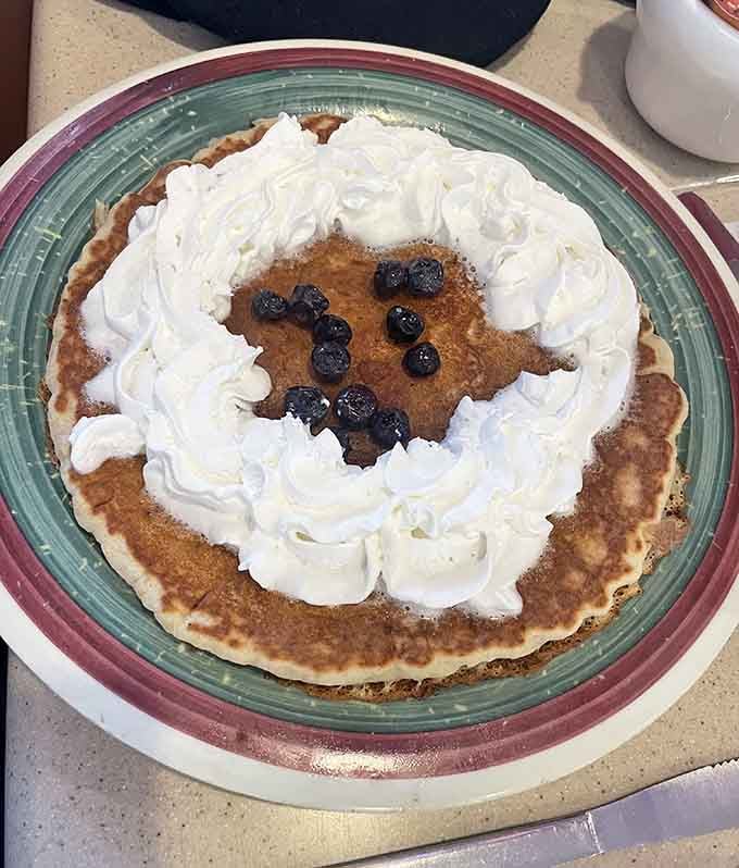 A pancake crowned with whipped cream and blueberries, because sometimes breakfast needs to feel like dessert.