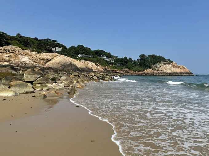 Smooth rocks and gentle surf create a natural border where land meets sea in timeless harmony.