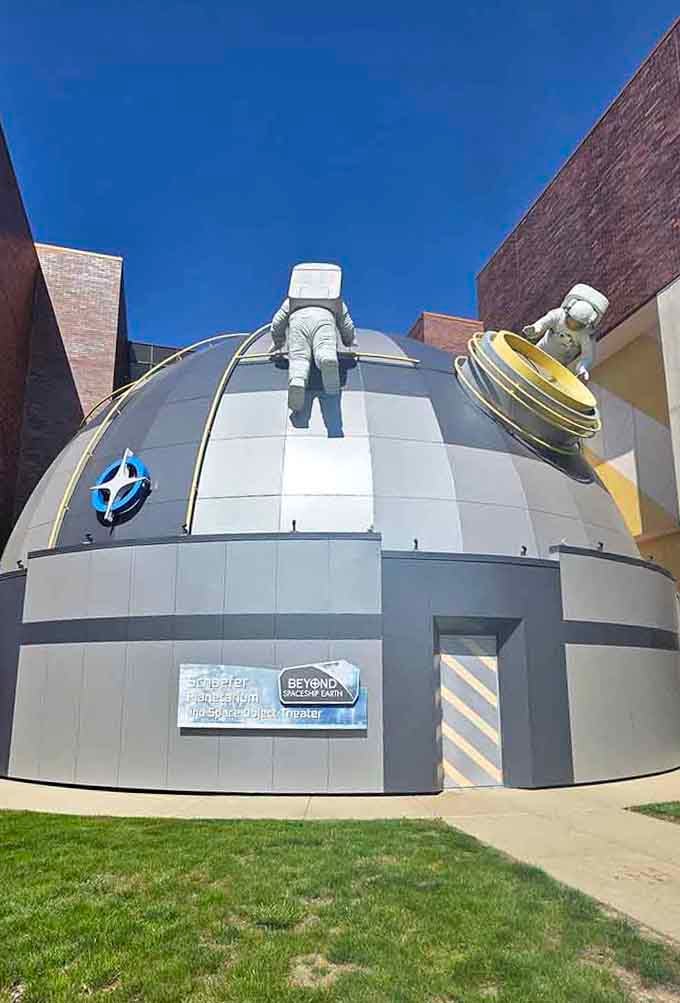 Astronauts scaling the planetarium because apparently even space explorers need to practice their climbing skills regularly.