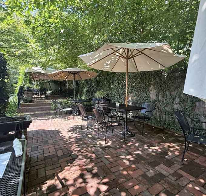 Brick patio shaded by umbrellas and climbing vines creates the perfect outdoor dining escape.