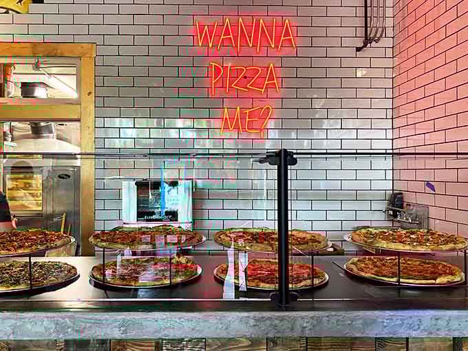 Neon "WANNA PIZZA ME?" signage adds cheeky humor to the pizza display that's impossible not to smile at.