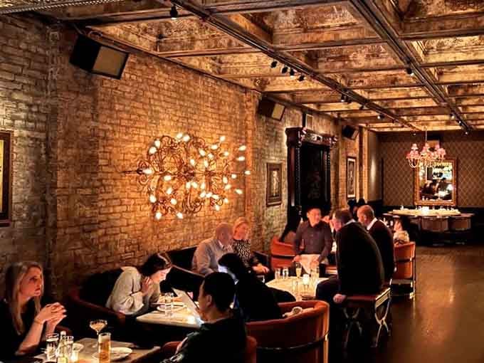The warm lighting and exposed brick walls make every diner look like they're starring in their own sophisticated dinner party scene.