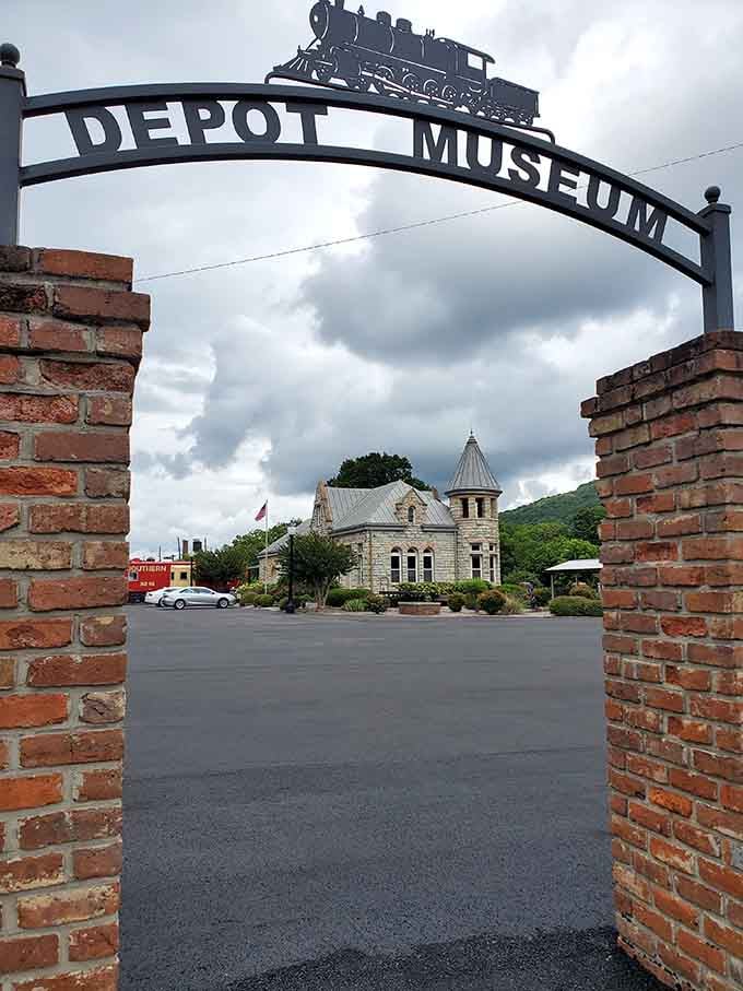 The arched entrance with its miniature locomotive promises railroad history and small-town stories waiting just beyond those brick pillars.
