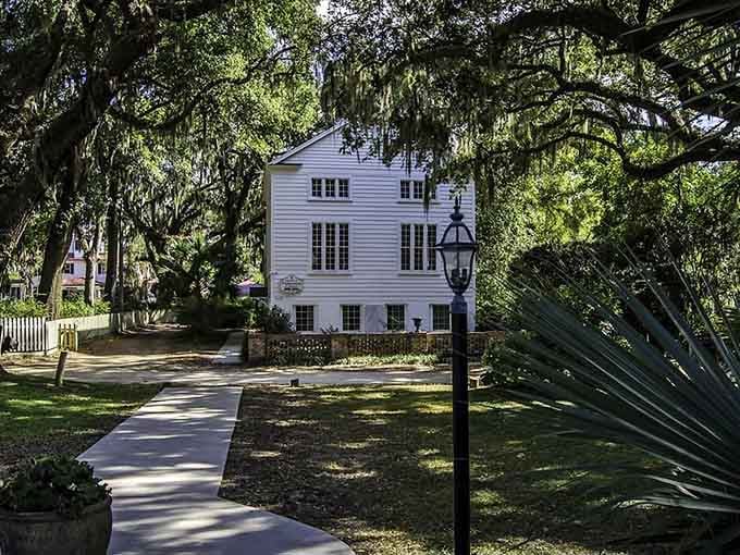 Spanish moss drapes ancient oaks over a pristine white building like nature's own elegant curtains.