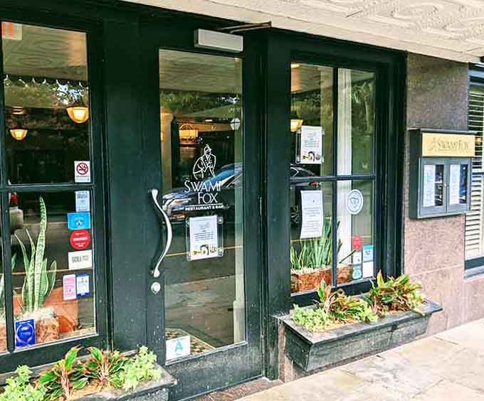 The hunter green storefront and planters filled with greenery create an urban oasis in the heart of downtown.