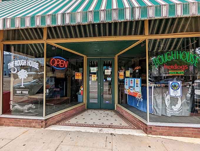 The Rough House storefront beckons with classic striped awning charm and promises of satisfying Southern comfort food.