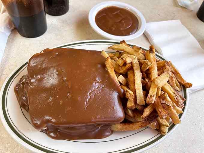 Hot roast beef sandwich swimming in gravy with fries, comfort food that hugs you from the inside out warmly.